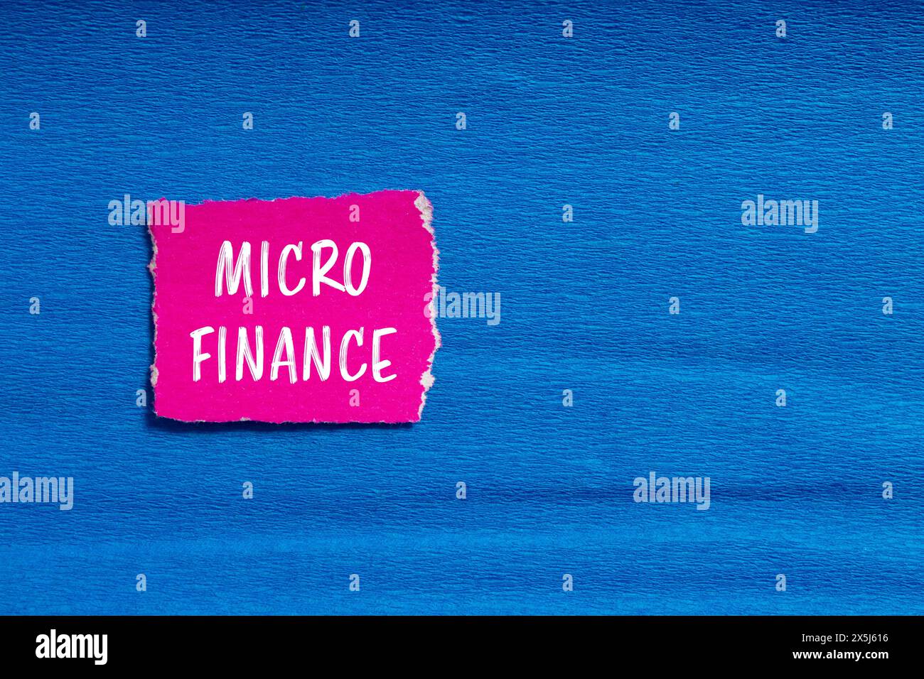 Micro finance words written on ripped pink paper piece with blue ...