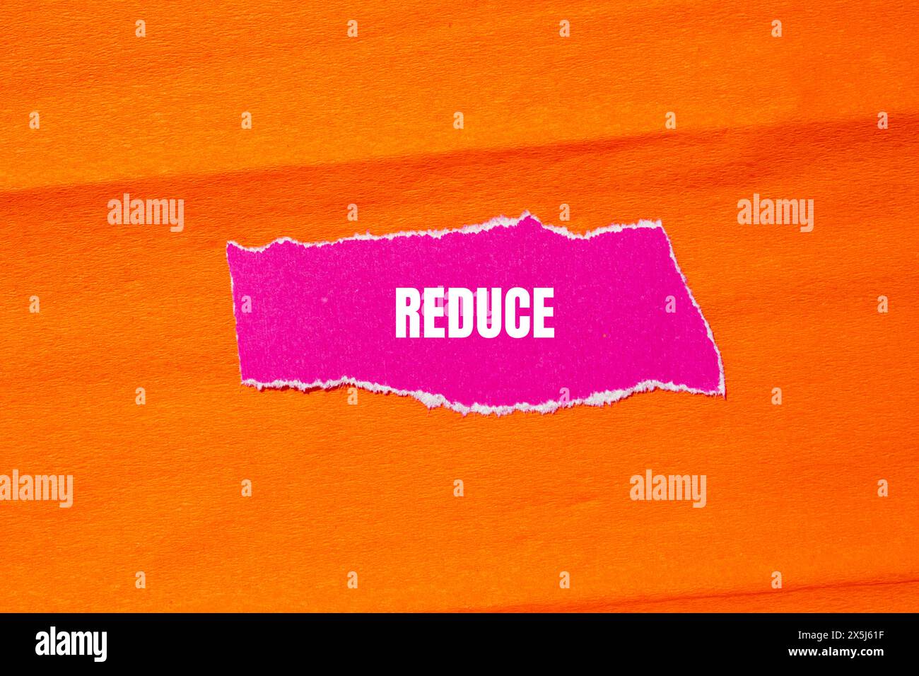 Reduce word written on ripped pink paper piece with blue background ...