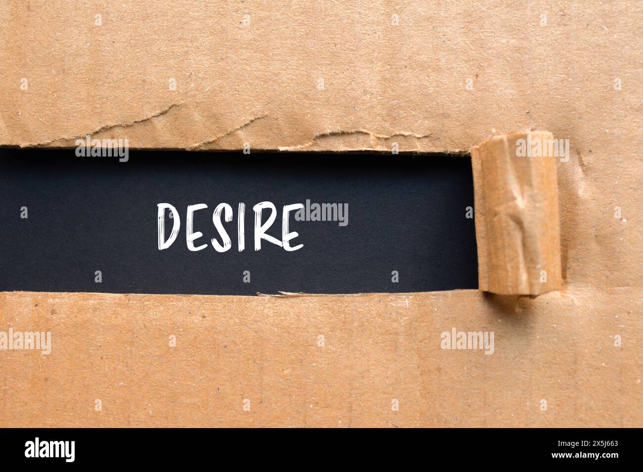 Desire word written on ripped cardboard paper with black background ...