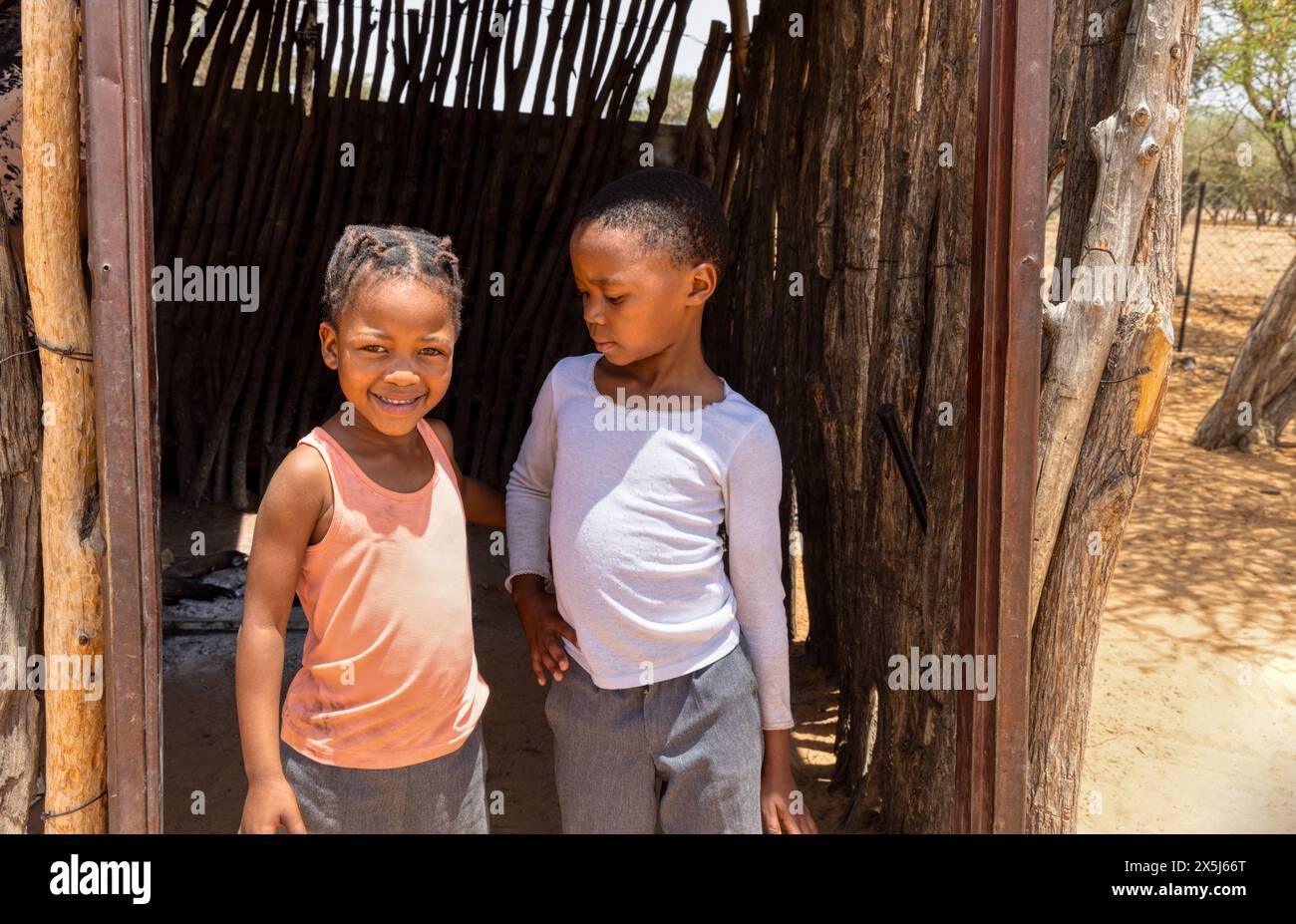 two village african girls with braids standing at the entrance of the ...