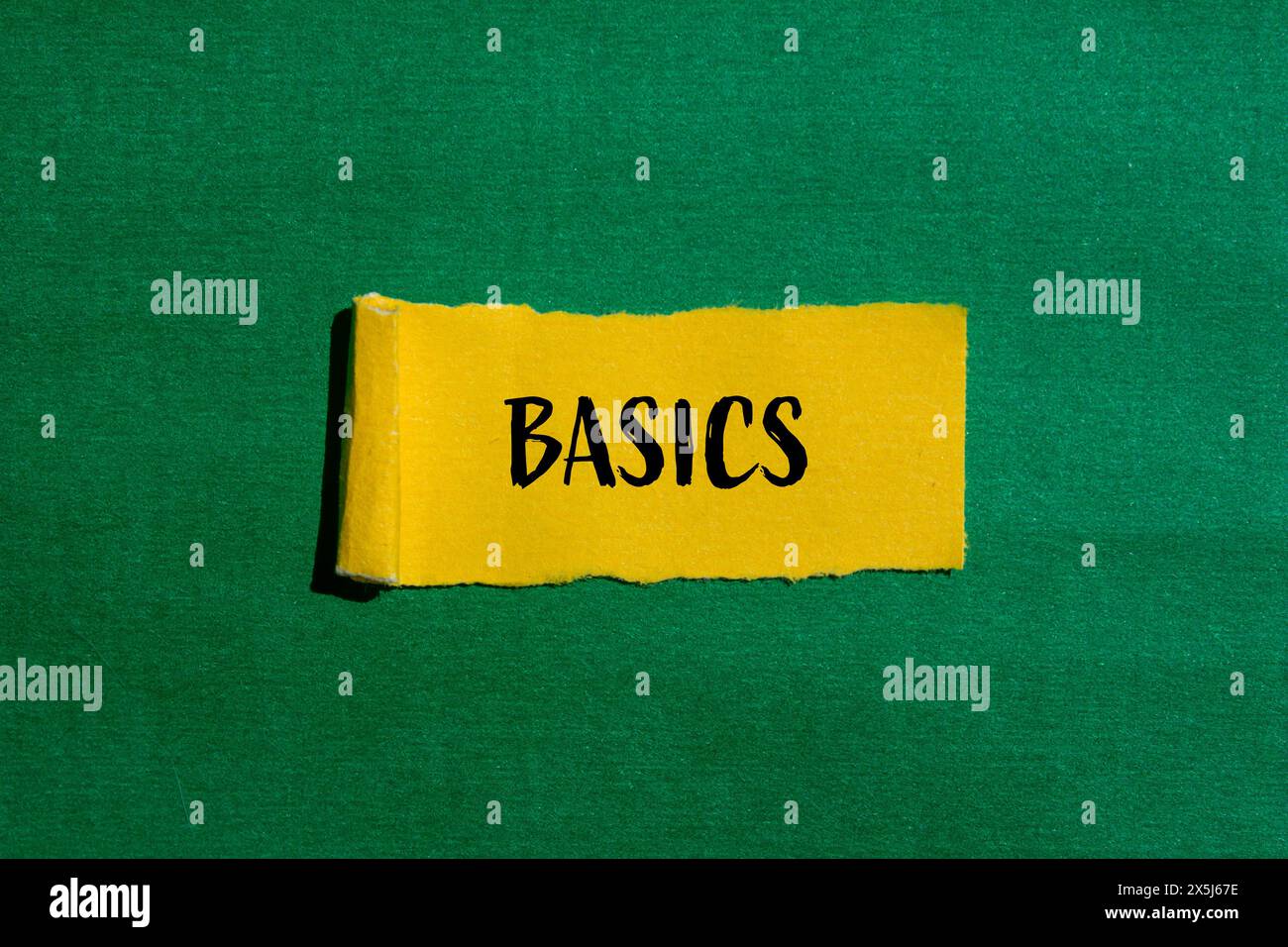 Basics word written on ripped yellow paper with green background ...