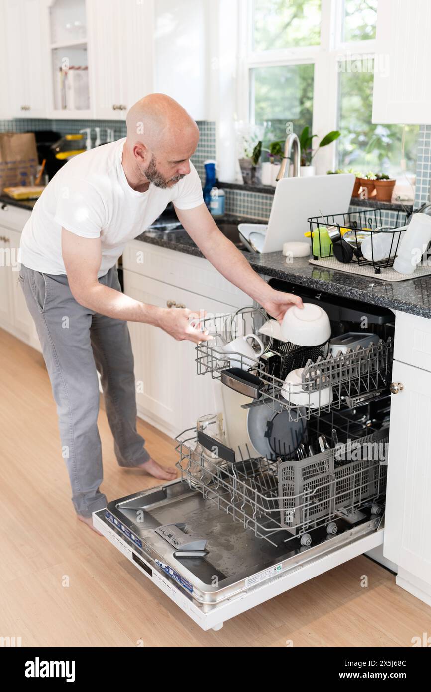 Man loading dishwasher on a sunny morning Stock Photo - Alamy