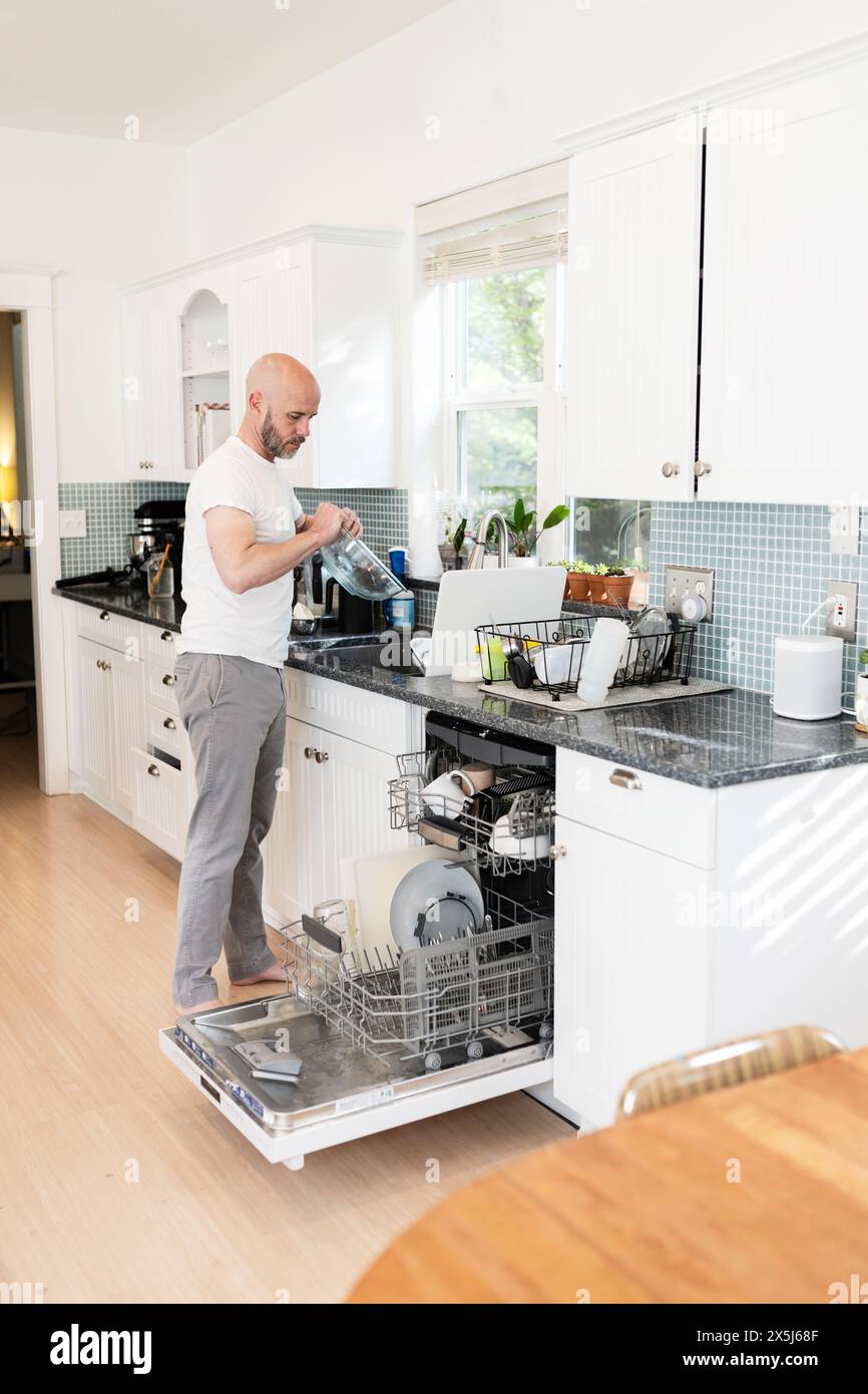 Man loading dirty dishes into dishwasher Stock Photo - Alamy
