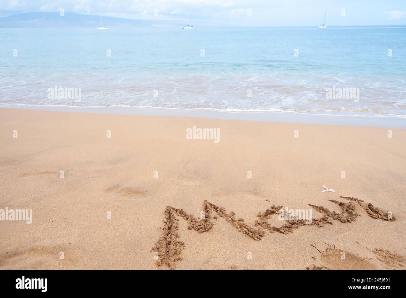 "Maui" written in sand with ocean and sailboats Stock Photo - Alamy