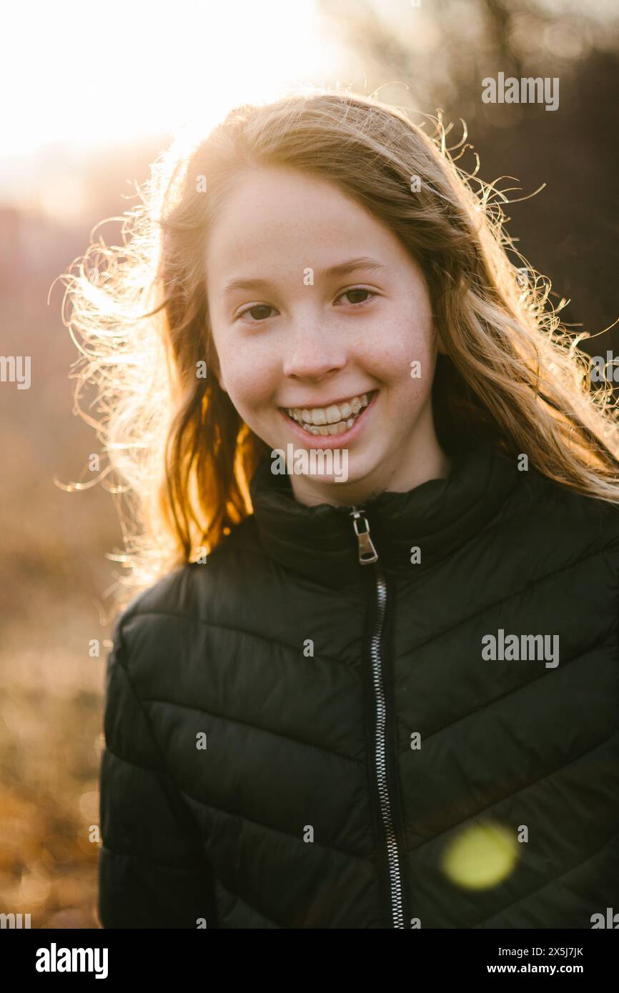 Tween girl smiling in golden sunlight on blond hair outside Stock Photo ...