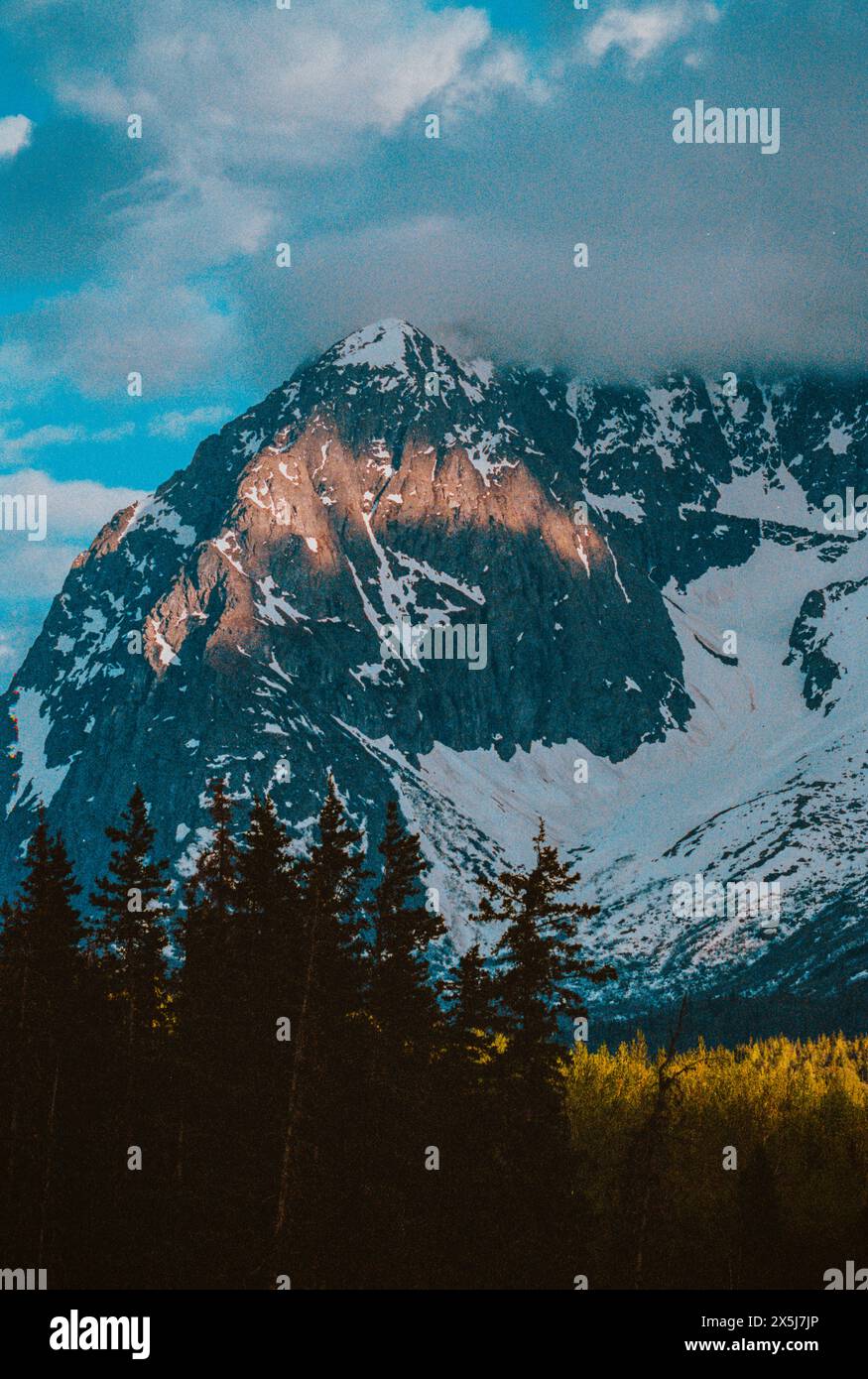 A patch of sun setting light touches a mountainside in Alaska Stock ...