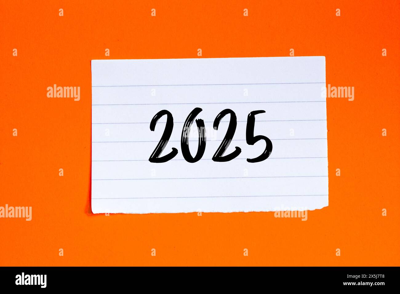 2025 written on torn paper with orange background. Conceptual new year 2025 symbol. Copy space ...