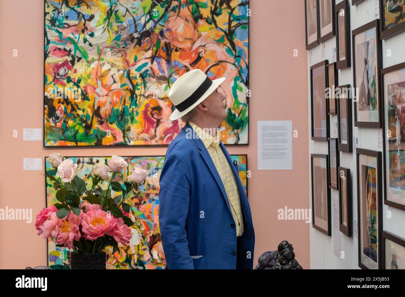 Man with straw panama hat observing paintings on the opening day at Art ...