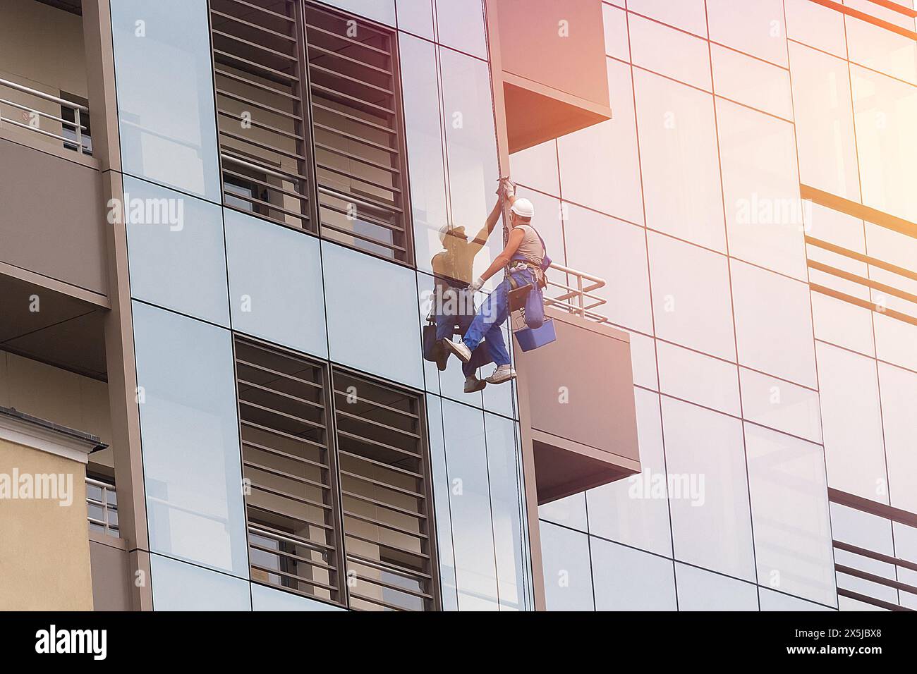 A male industrial climber washes the windows of a tall modern ...
