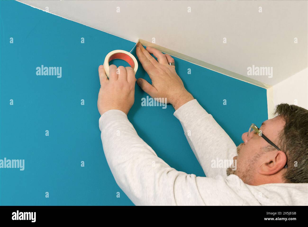 Attaching masking tape to the ceiling for painting Stock Photo - Alamy