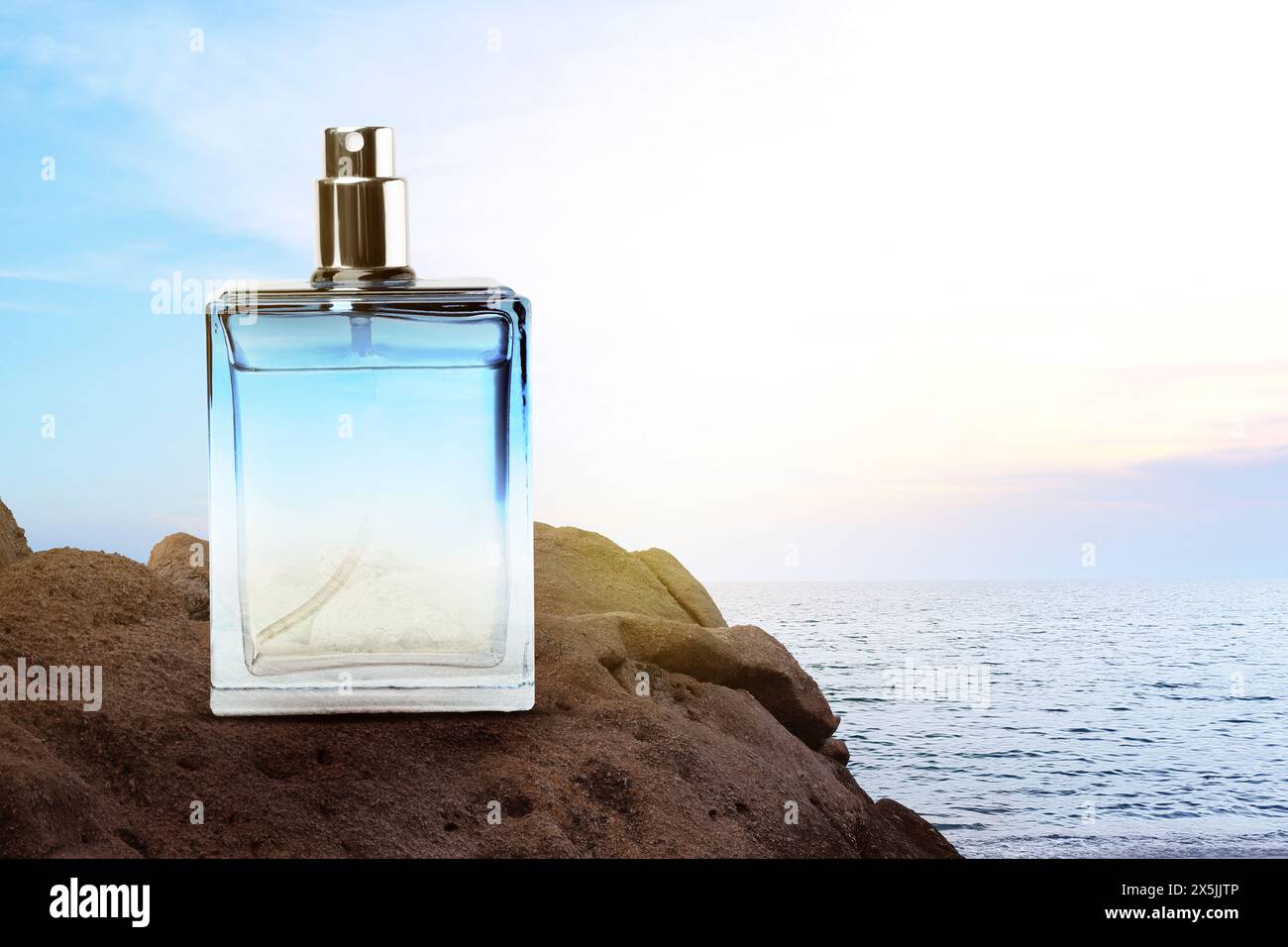 Bottle of aquatic perfume on rock near ocean. Fresh sea breeze scent ...