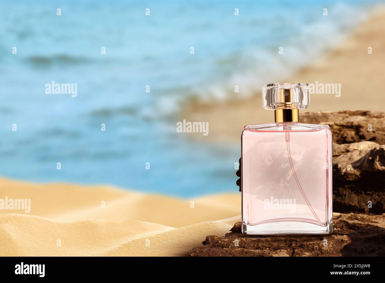 Bottle of aquatic perfume on rock near ocean. Fresh sea breeze scent ...