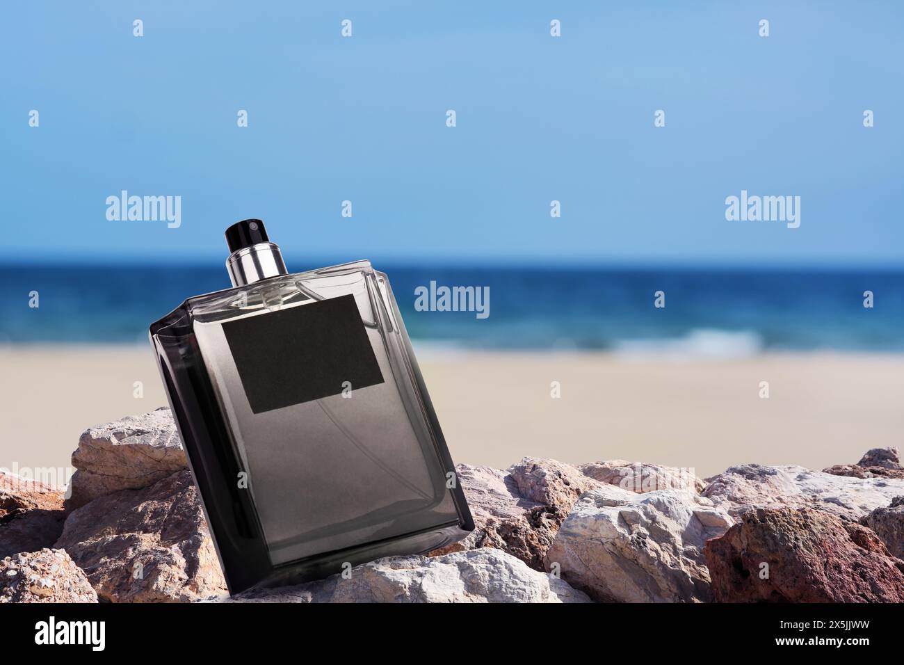 Bottle of aquatic perfume on stones near ocean. Fresh sea breeze scent ...