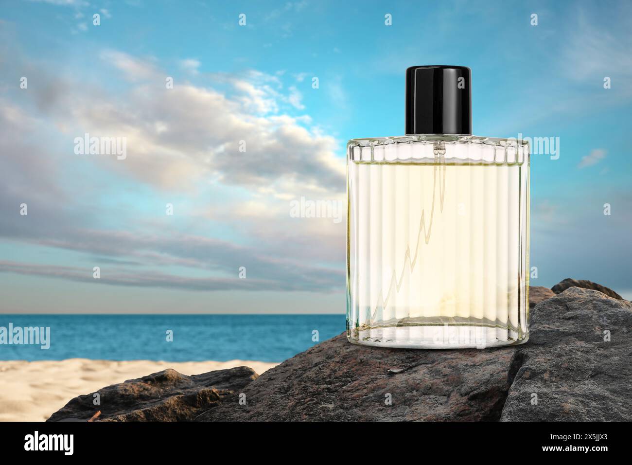 Bottle of aquatic perfume on rock near ocean. Fresh sea breeze scent ...