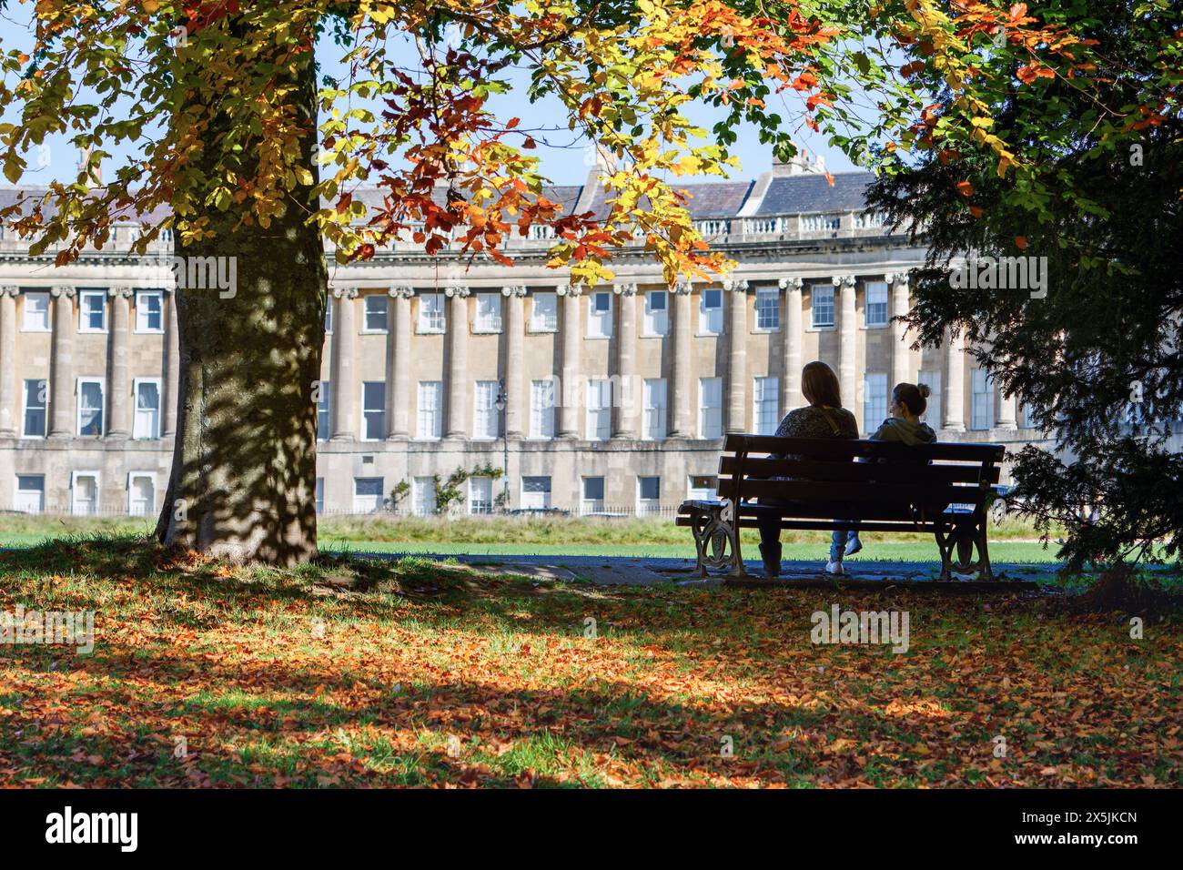 Two women bask in the autumn sunshine, sitting peacefully in front of ...