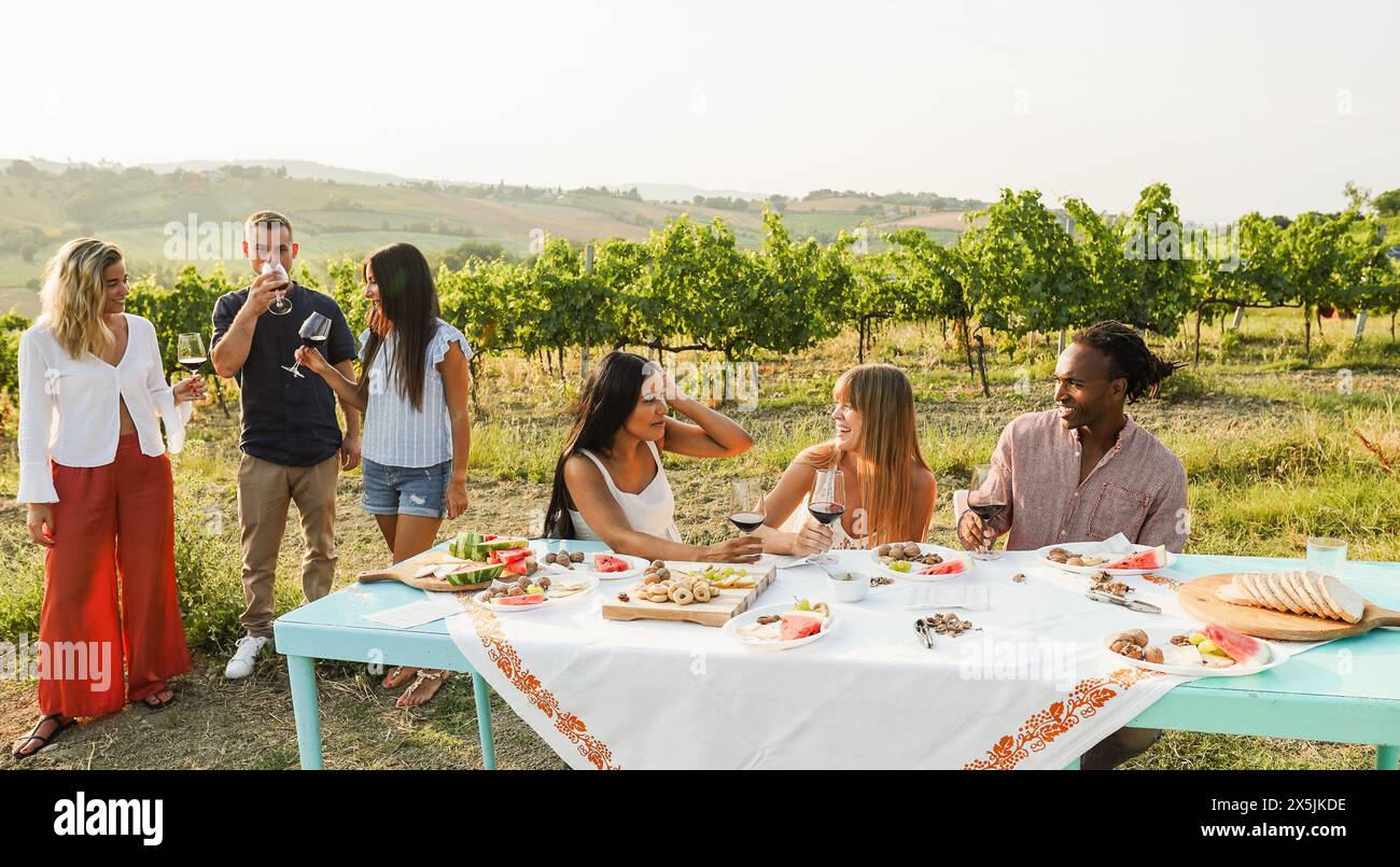 Happy friends having fun drinking red wine and eating together with ...