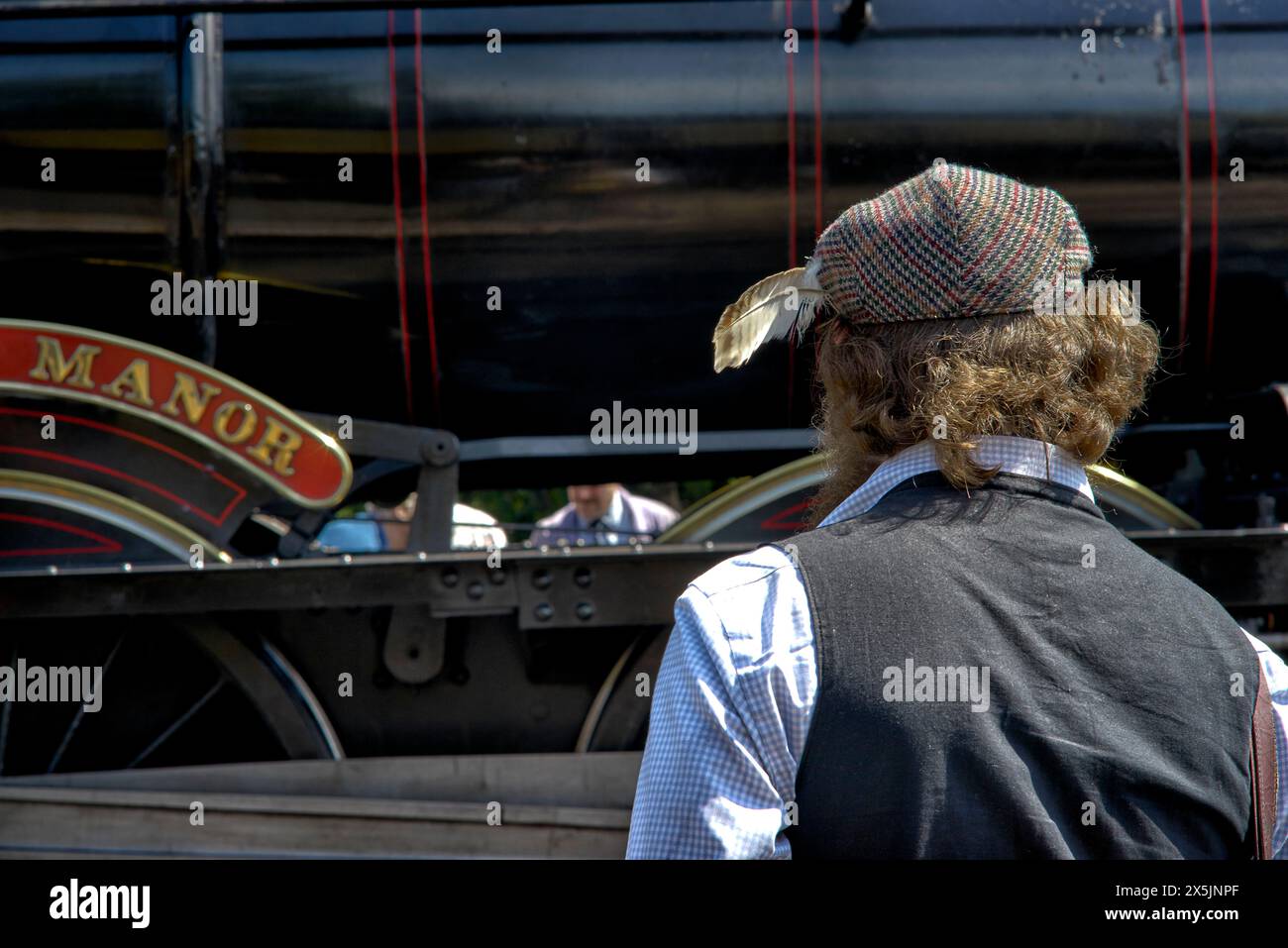 Feather in cap. Man with birds feather in his cap admiring a steam ...