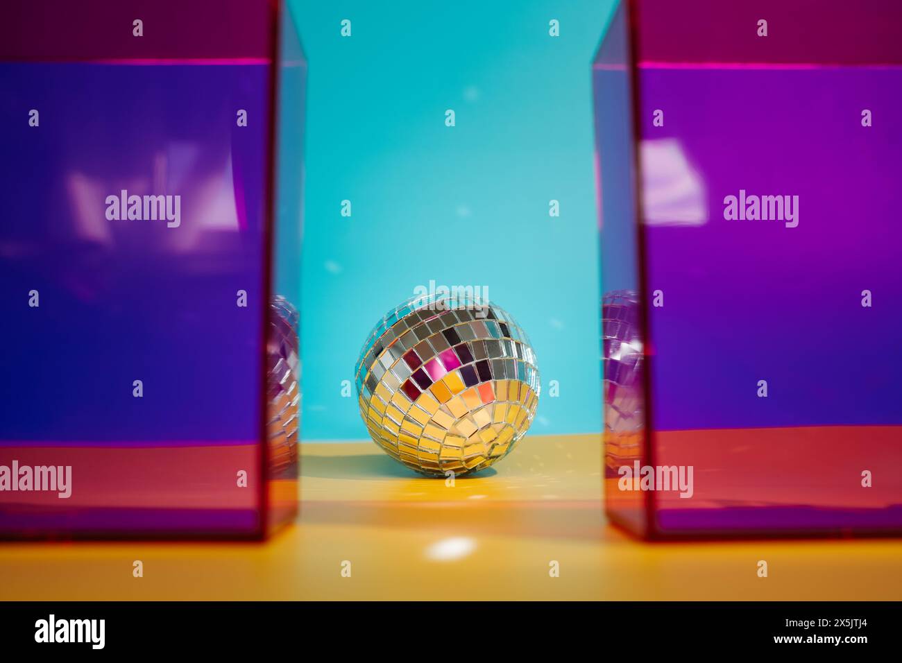 Mirror disco ball on yellow and blue background with vivid pink ...