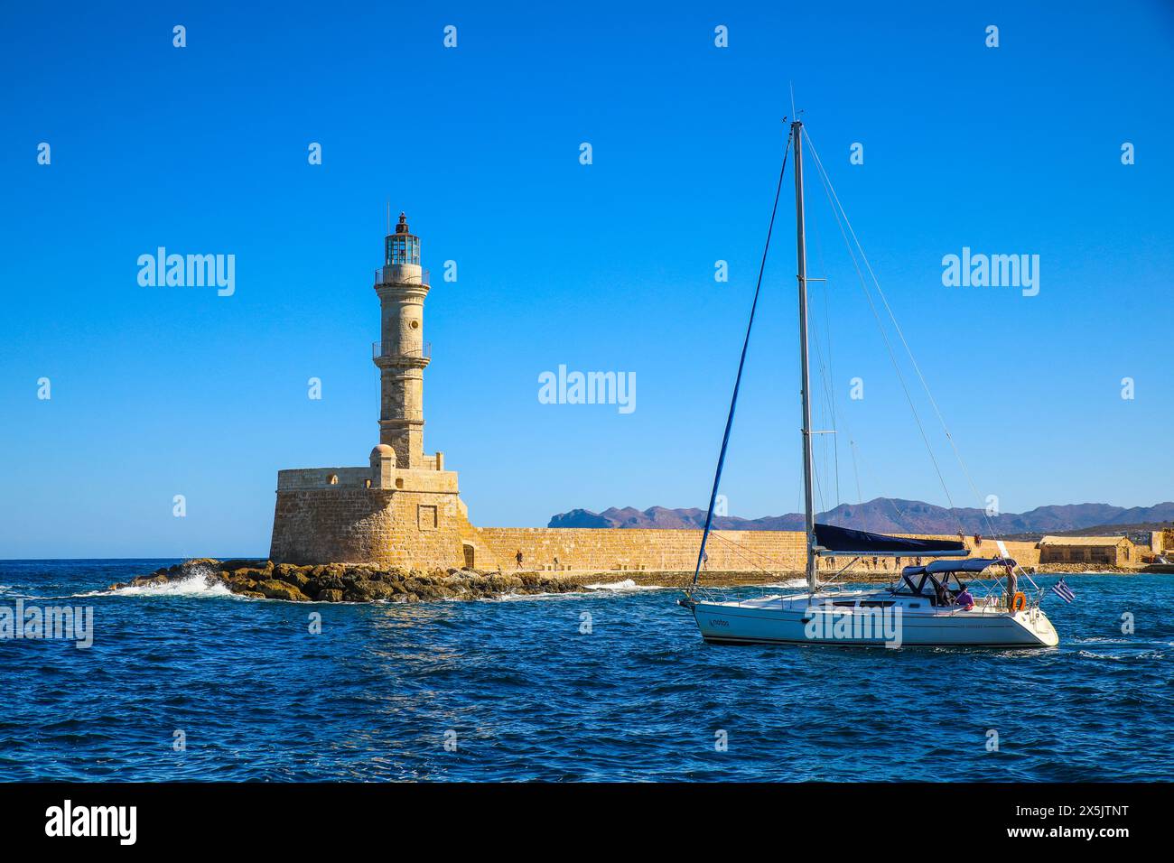 Chania, Greece. Sailing past limestone Chania lighthouse in a sailboat on the bay. (Editorial ...