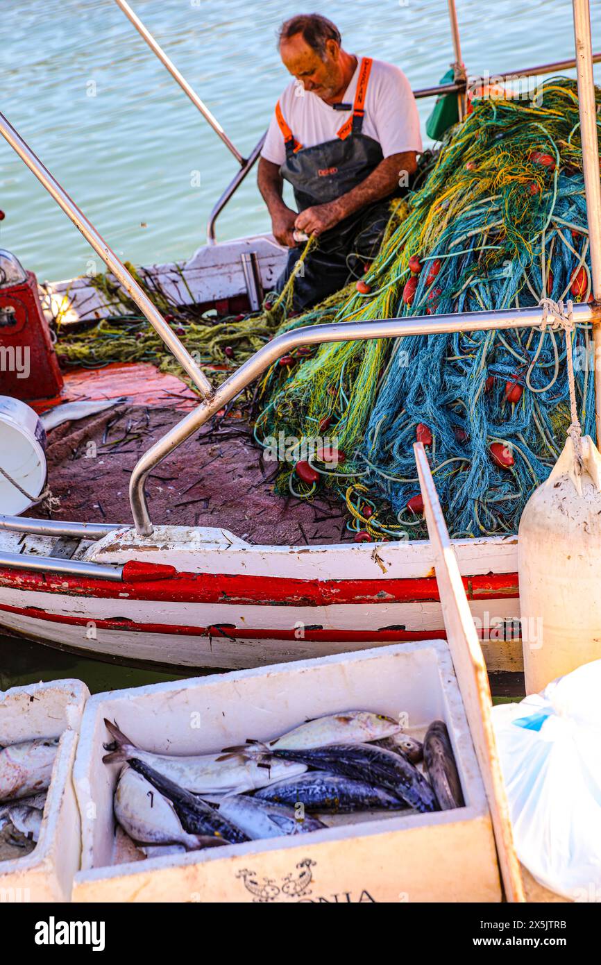 Argostoli, Greece. Fisherman repairs fishing nets on his boat and his ...