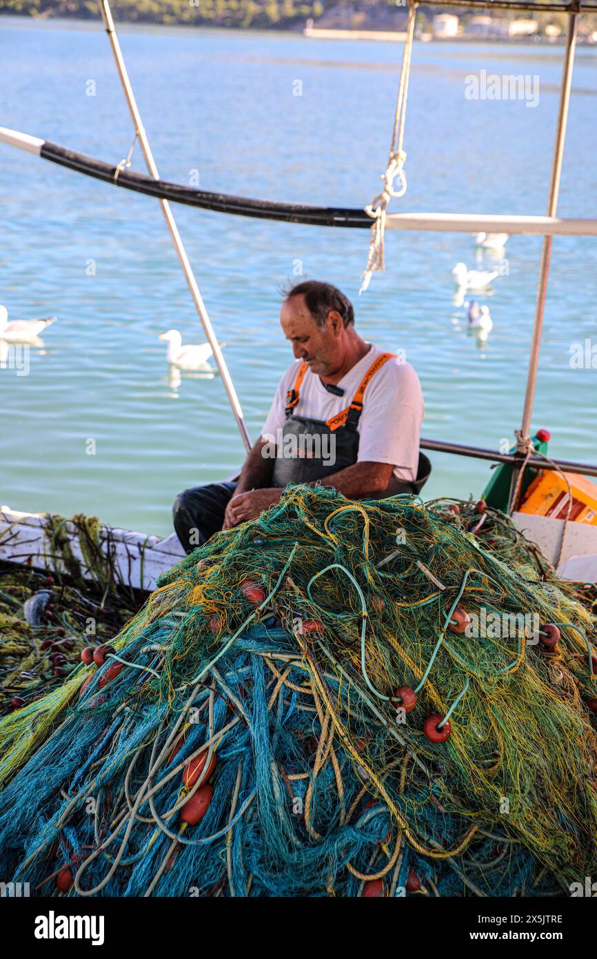 Greece. Greek fisherman works with his blue, green nets and buoys on ...