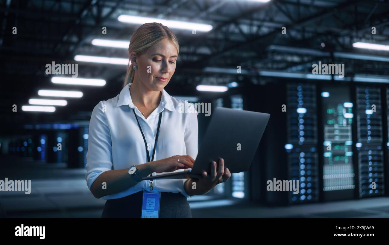 Female Data Center IT Technician Standing at the Server Rack Corridor ...