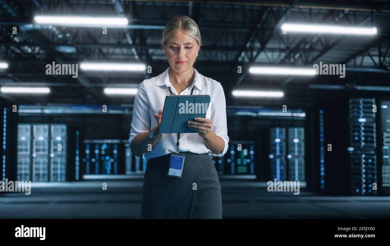 Blonde IT Specialist Using Tablet Computer in Data Center, Walking on a Bridge Overlooking Big ...