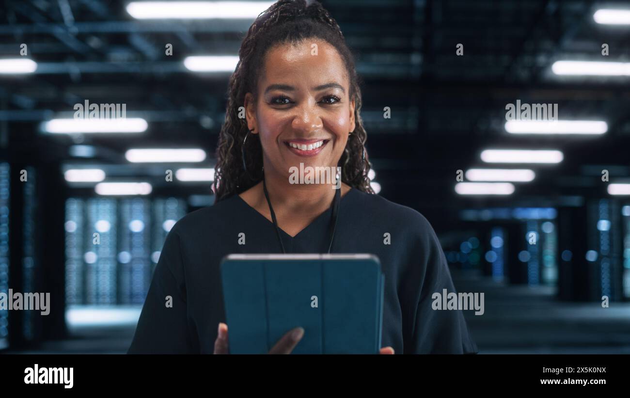 Portrait of the Cheerful Female IT Specialist Using Tablet Computer in Data Center, while ...