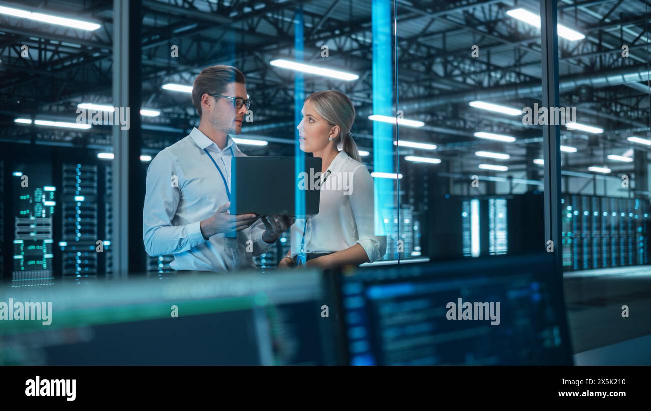 Two It Engineers Standing In Working Data Center They Use Laptop While