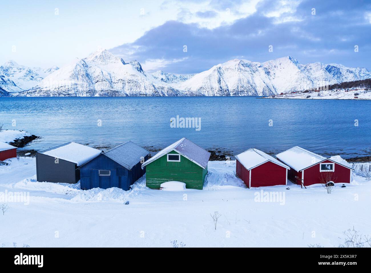 Colorful wooden rorbu covered with snow in the icy landscape by the ...