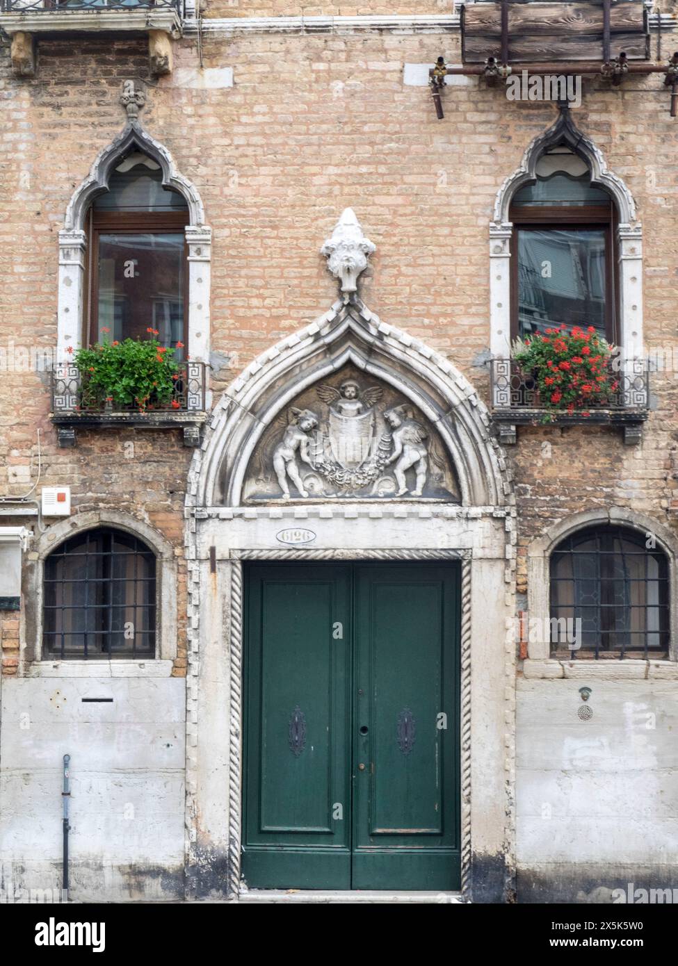 Italy, Venice. Venetian doorway and windows with colorful flowers boxes ...
