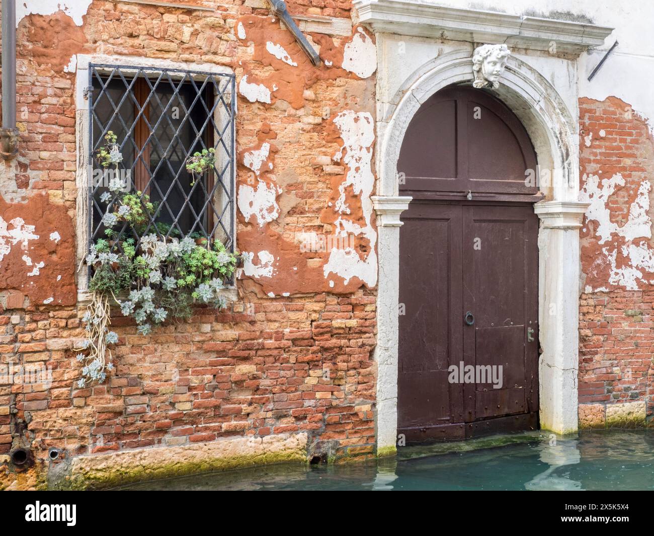 Italy, Venice. An old Venetian brick wall with flaking plaster along ...