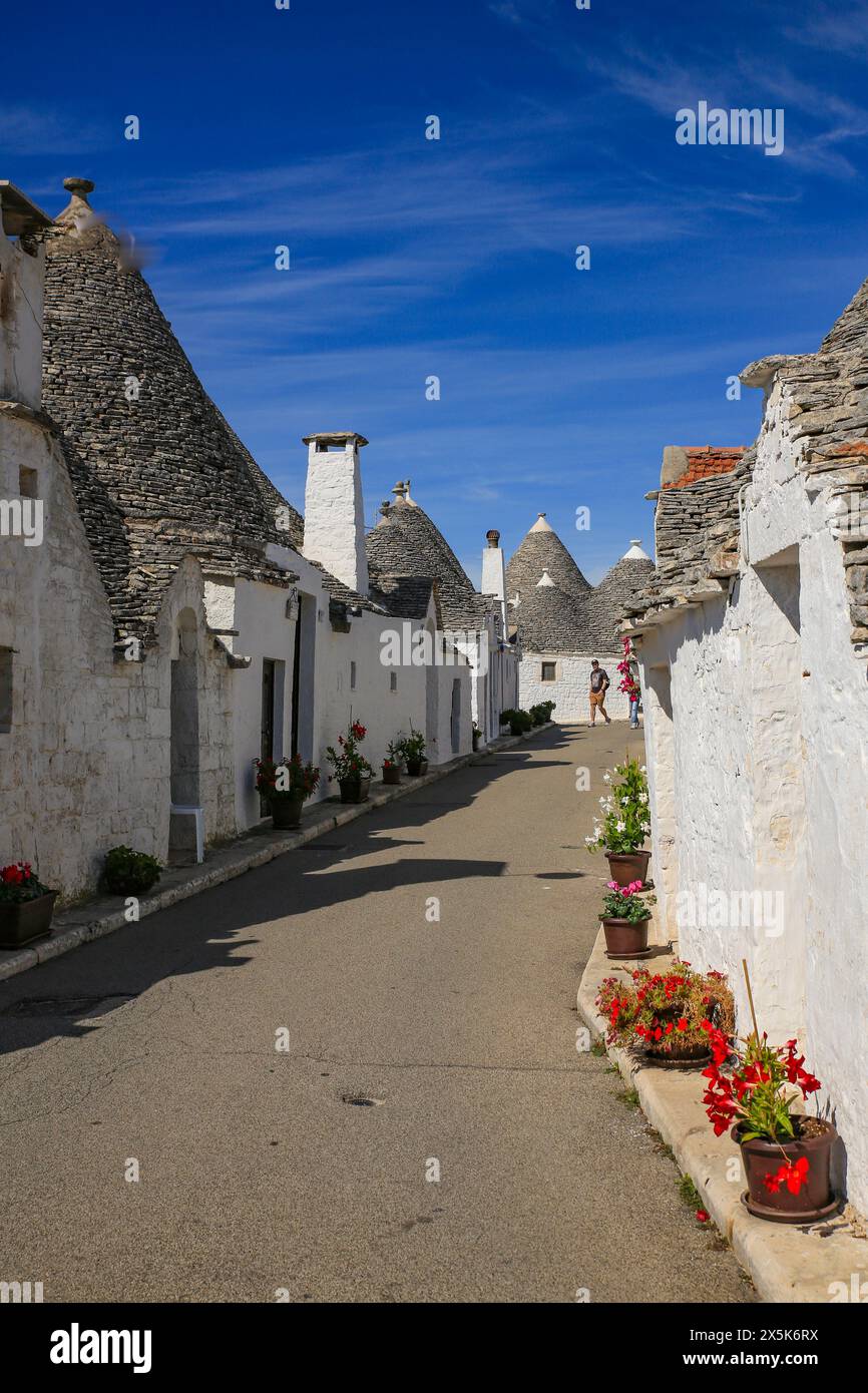 Alberobello, Italy. People walk down a Alberobello street, white washed ...