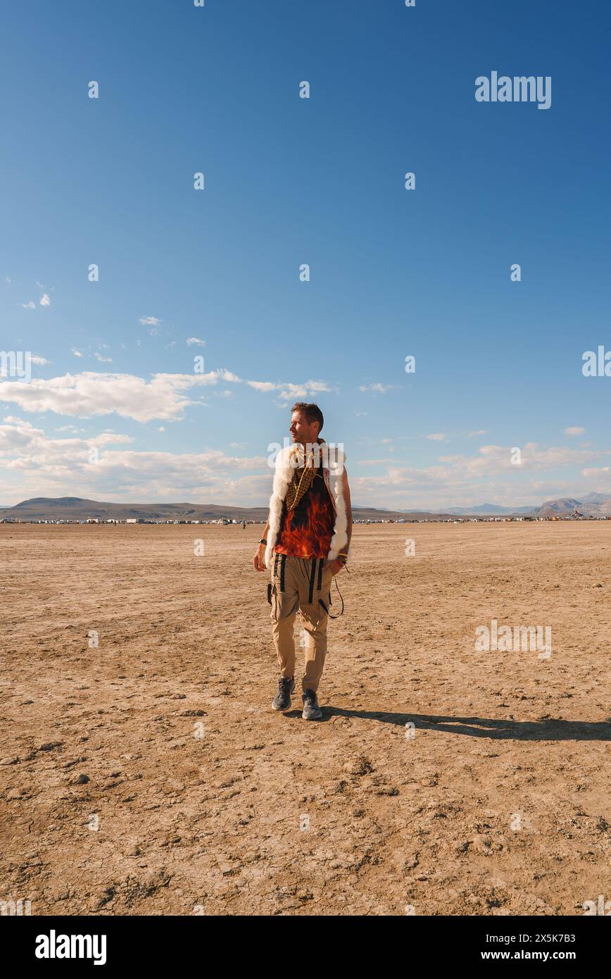 Alone figure in eclectic outfit, desert landscape, distant mountains ...
