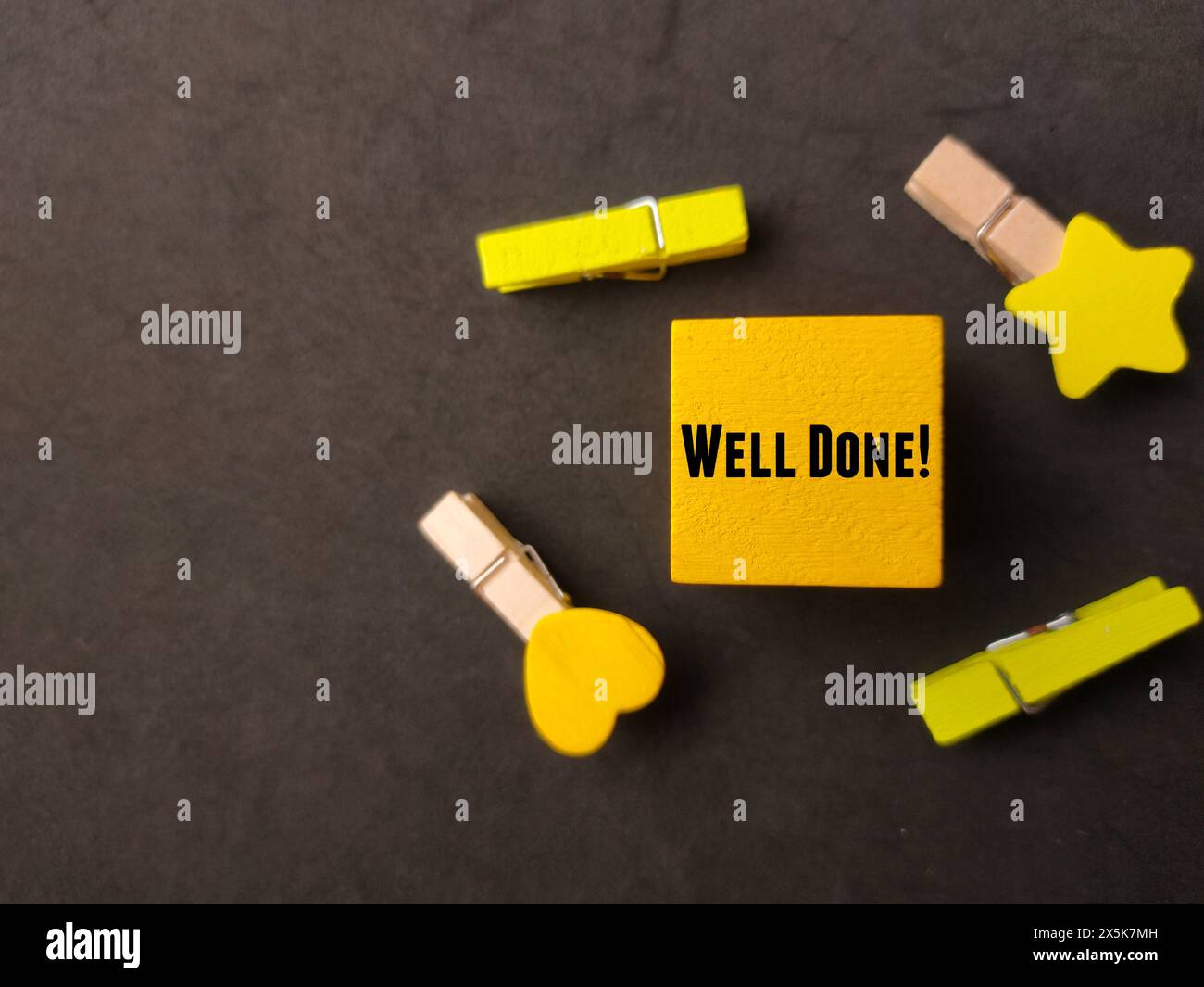 Top view colored block and wooden clips with text WELL DONE on a black ...