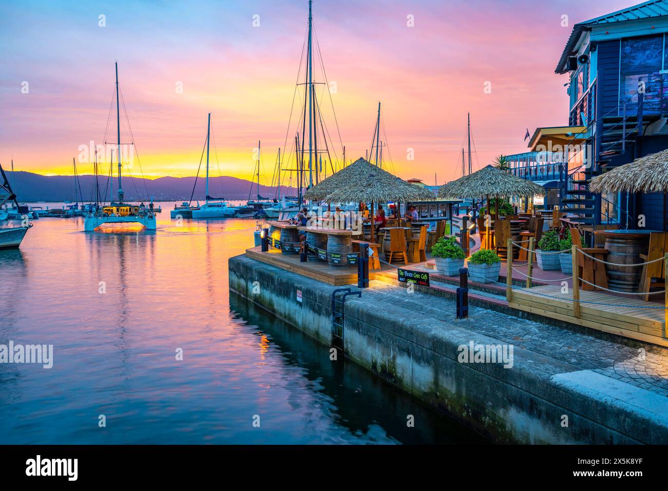 View of golden sunset, boats and restaurants at Knysna Waterfront ...