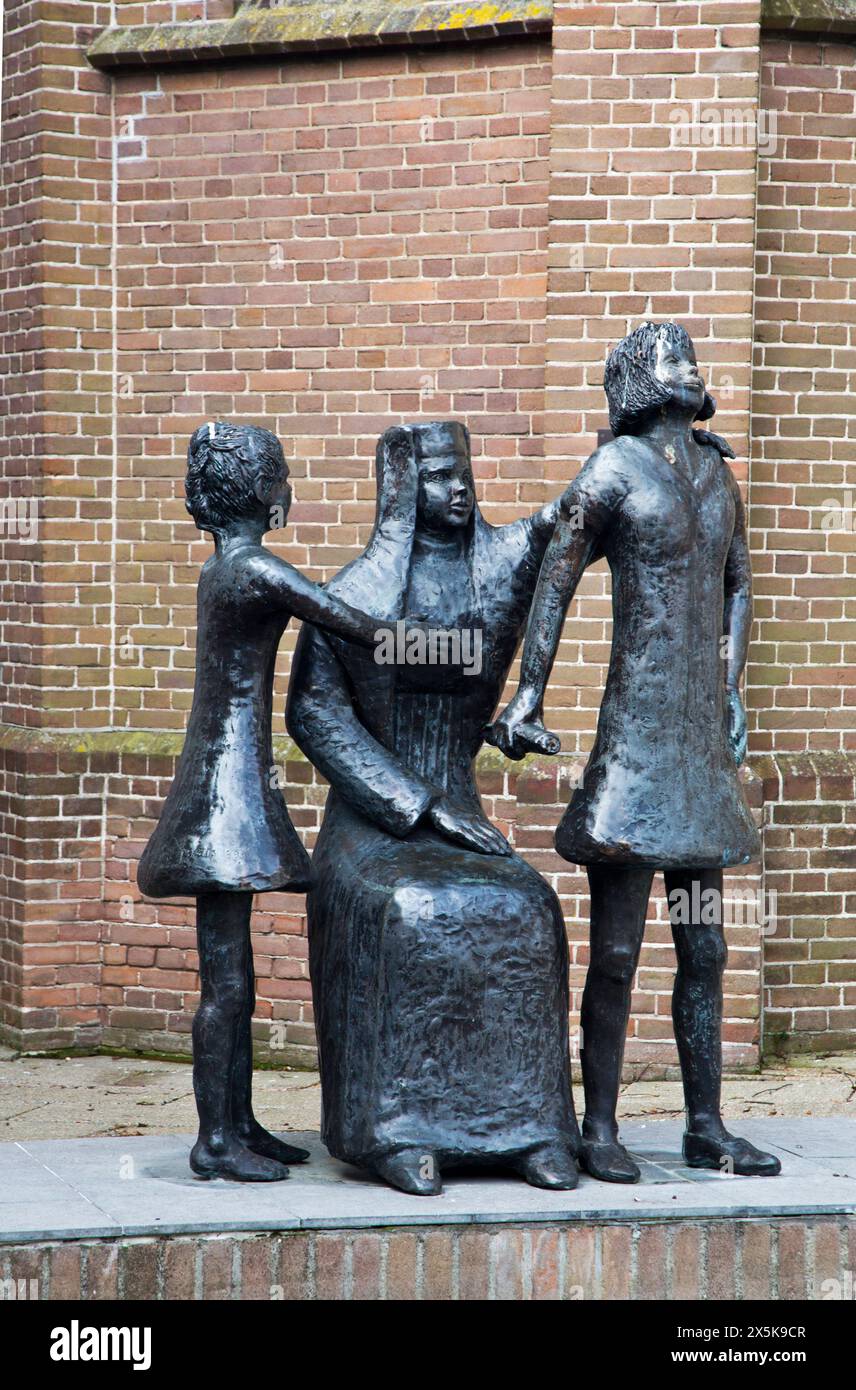 Bronze statue of a seated sister with two students. The statue stands ...