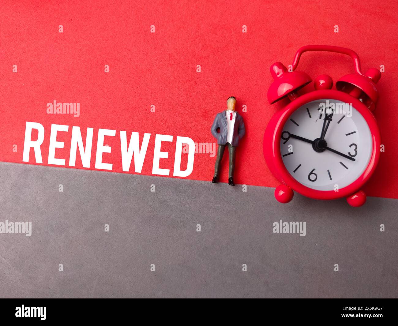 Top view miniature people and clock with text RENEWED on red and gray ...