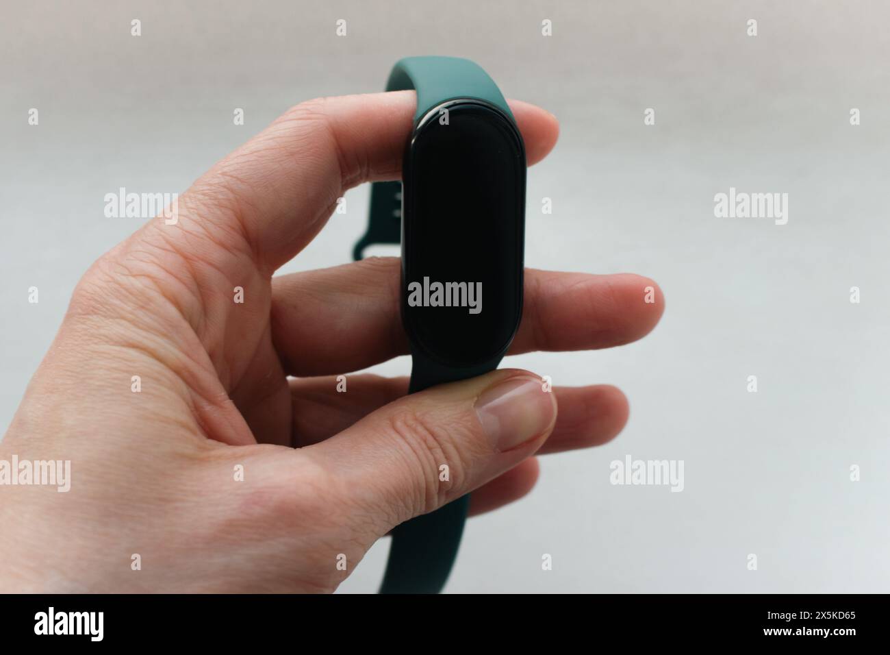 Hand holding fitness tracker with mockup screen and green strap on ...