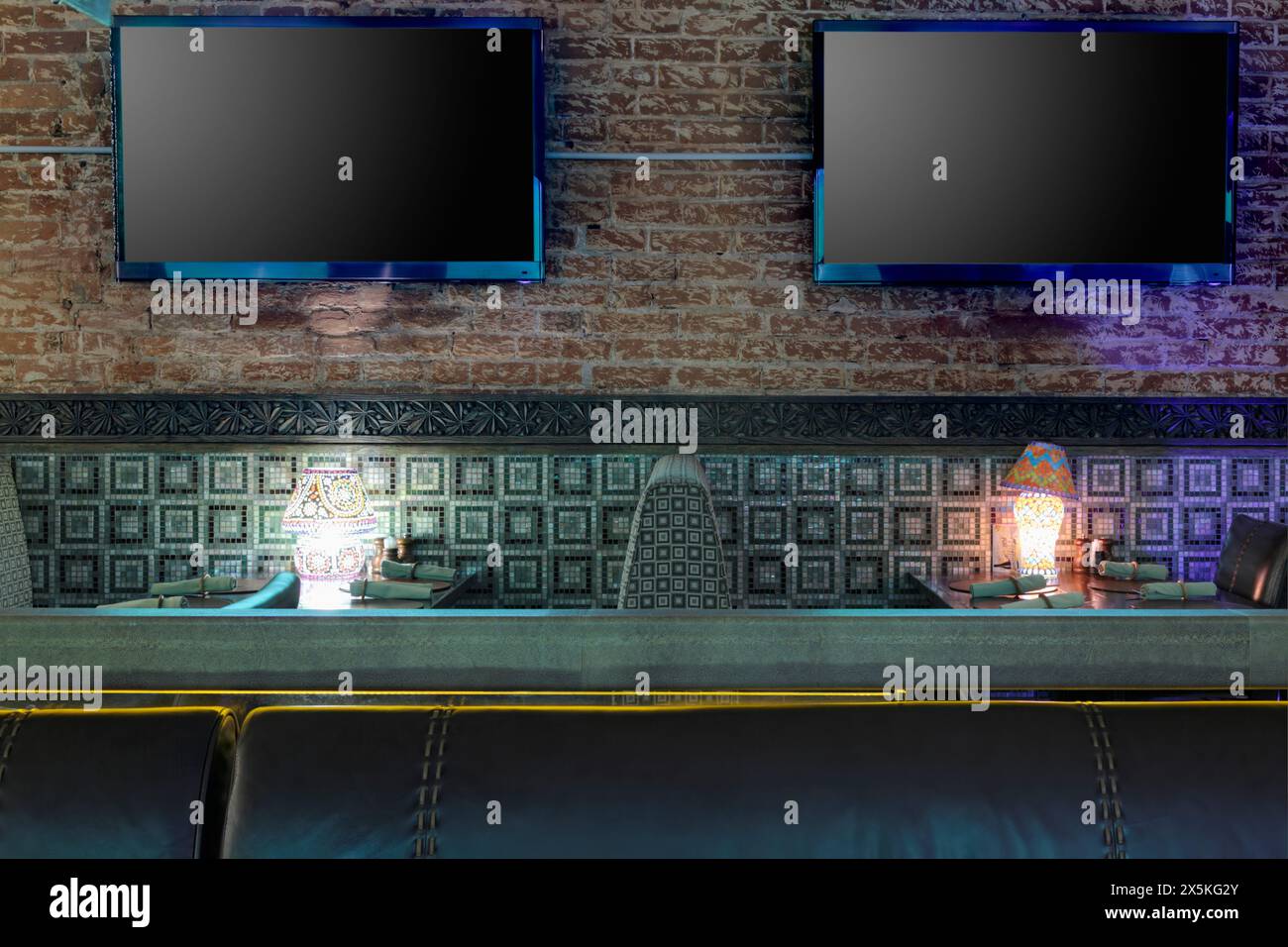 Restaurant tables with lamps under flat screen TVs Stock Photo - Alamy