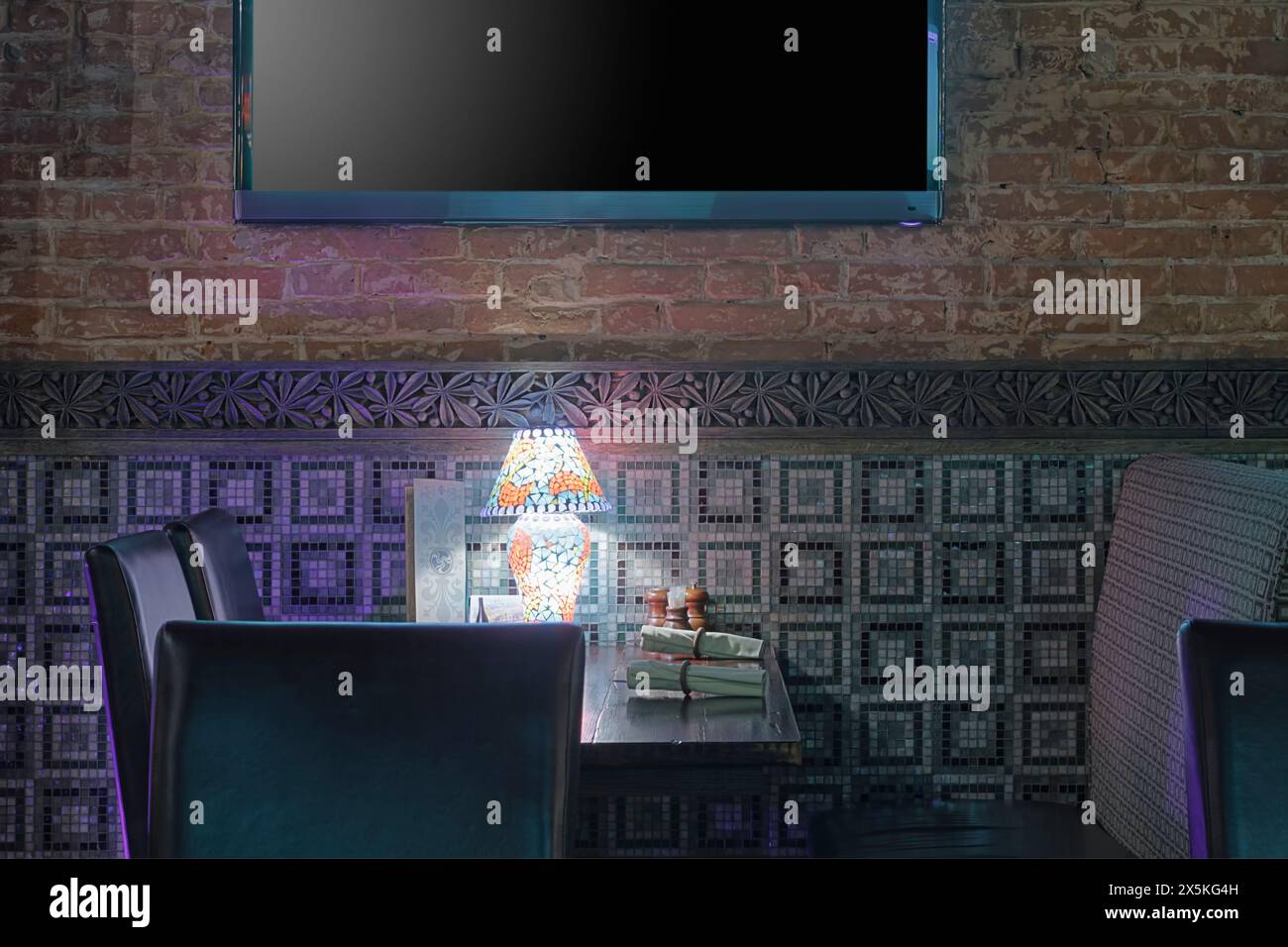 Restaurant table with lamp under flat screen TV Stock Photo - Alamy