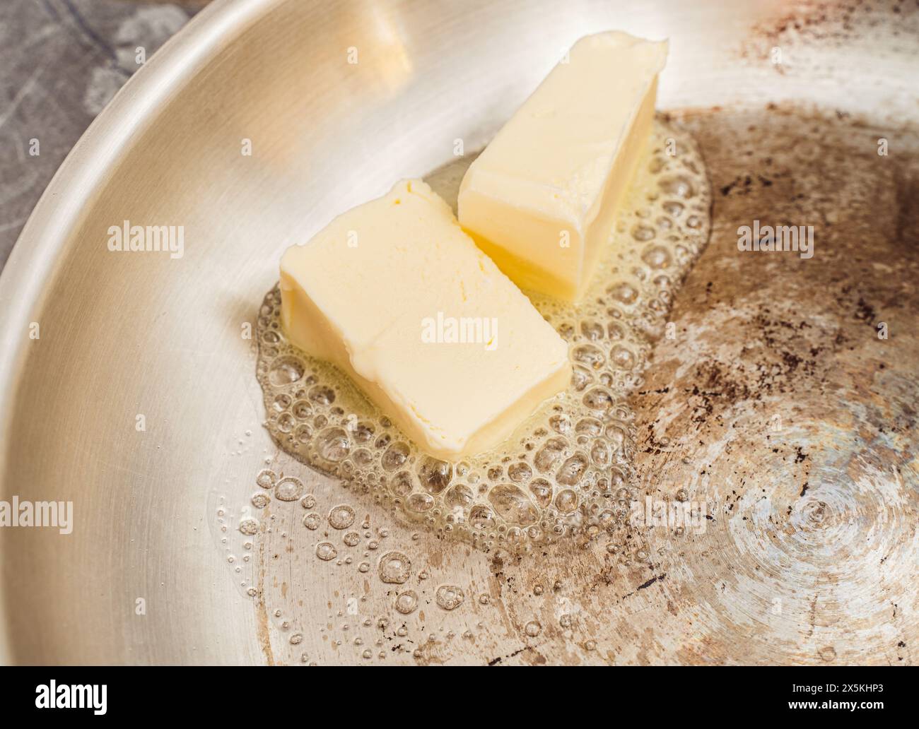Butter melts in pieces and sizzles in a frying pan close-up. Crepe ...