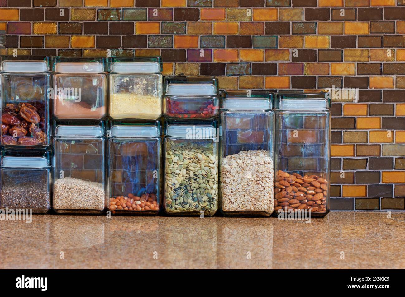 A kitchen in a home with a tiled wall, counter top with food storage ...
