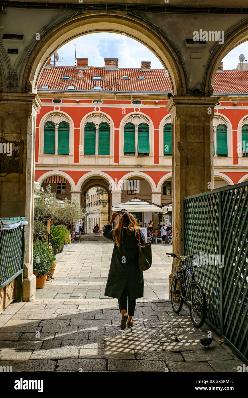 Split, Croatia. Woman walks through an archway towards the open air ...