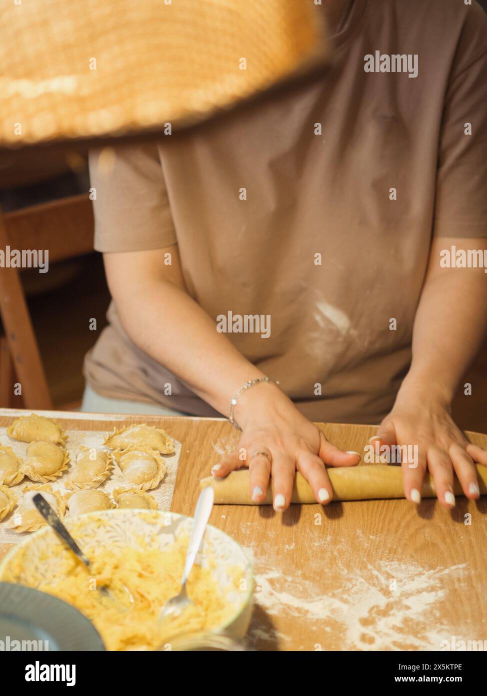 A vertical close-up captures a woman making dumplings, her face ...