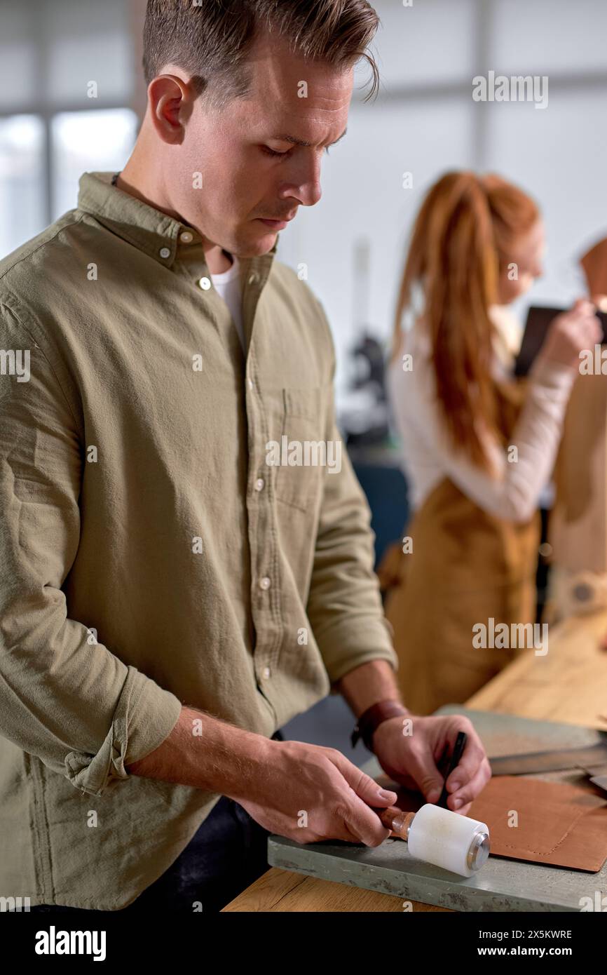 serious ambitious craftsman making patterns in leather goods, close up ...
