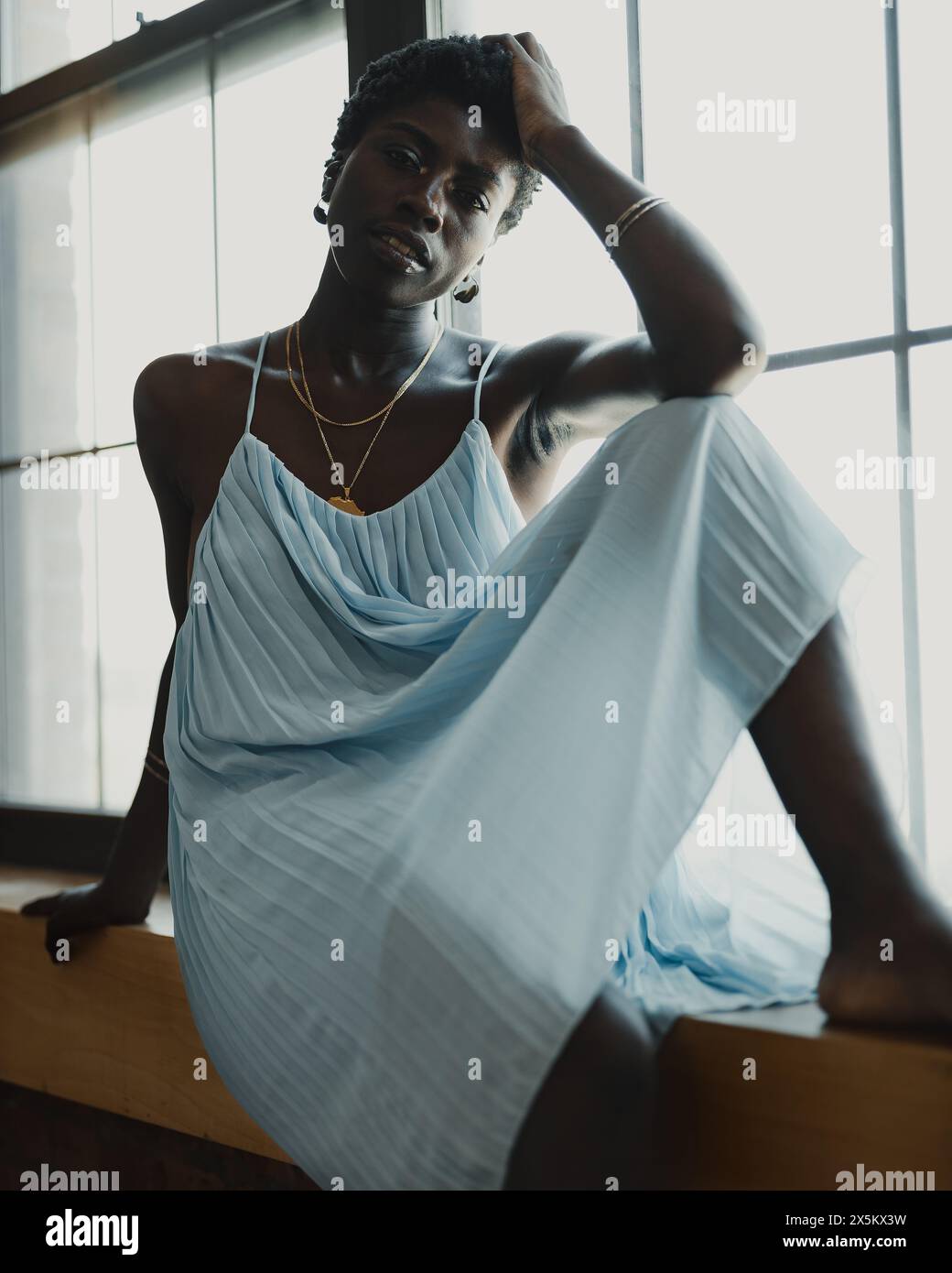USA, New York, Portrait of woman in white dress sitting by window Stock ...