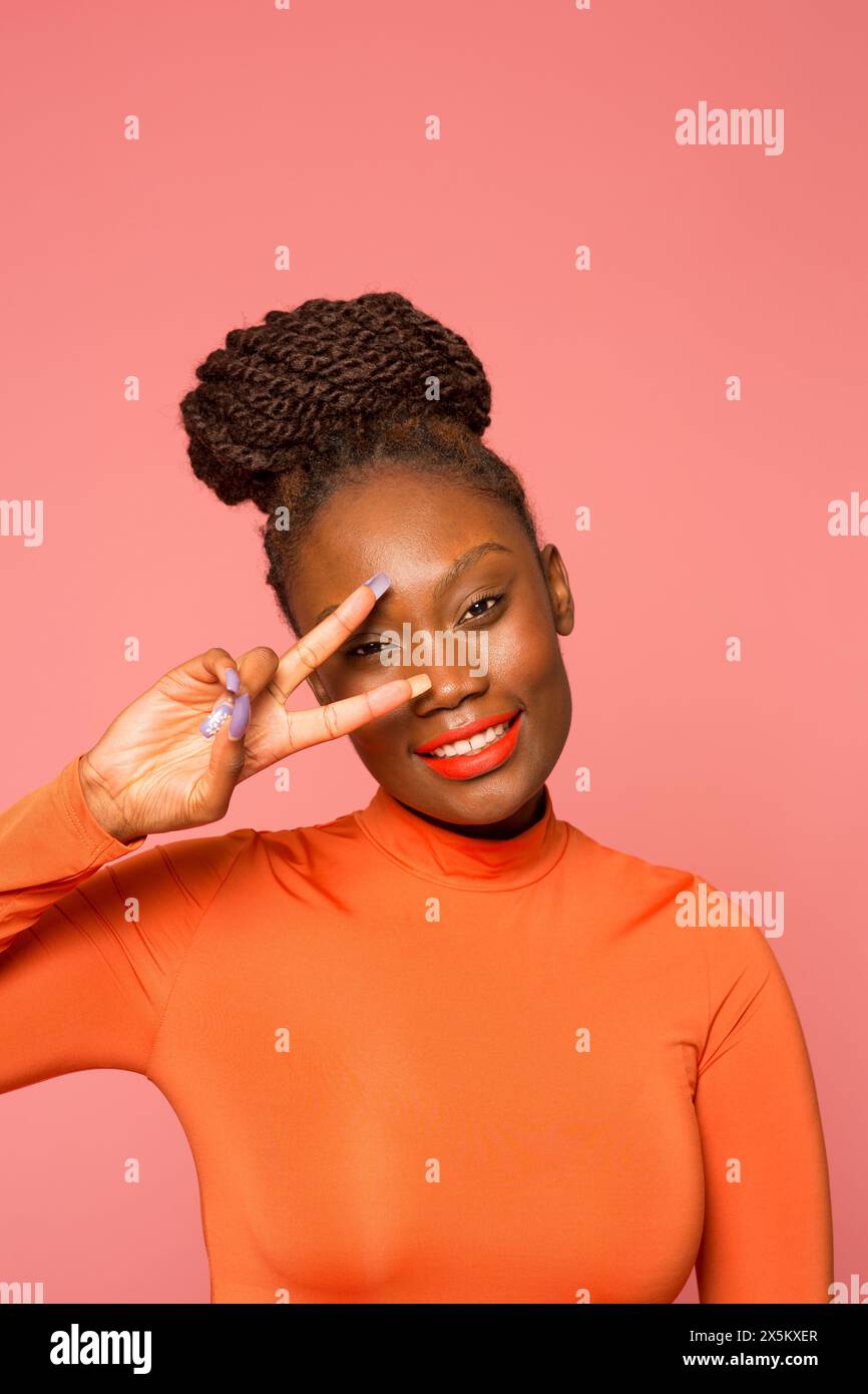 Studio portrait of stylish woman sowing peace sign Stock Photo - Alamy