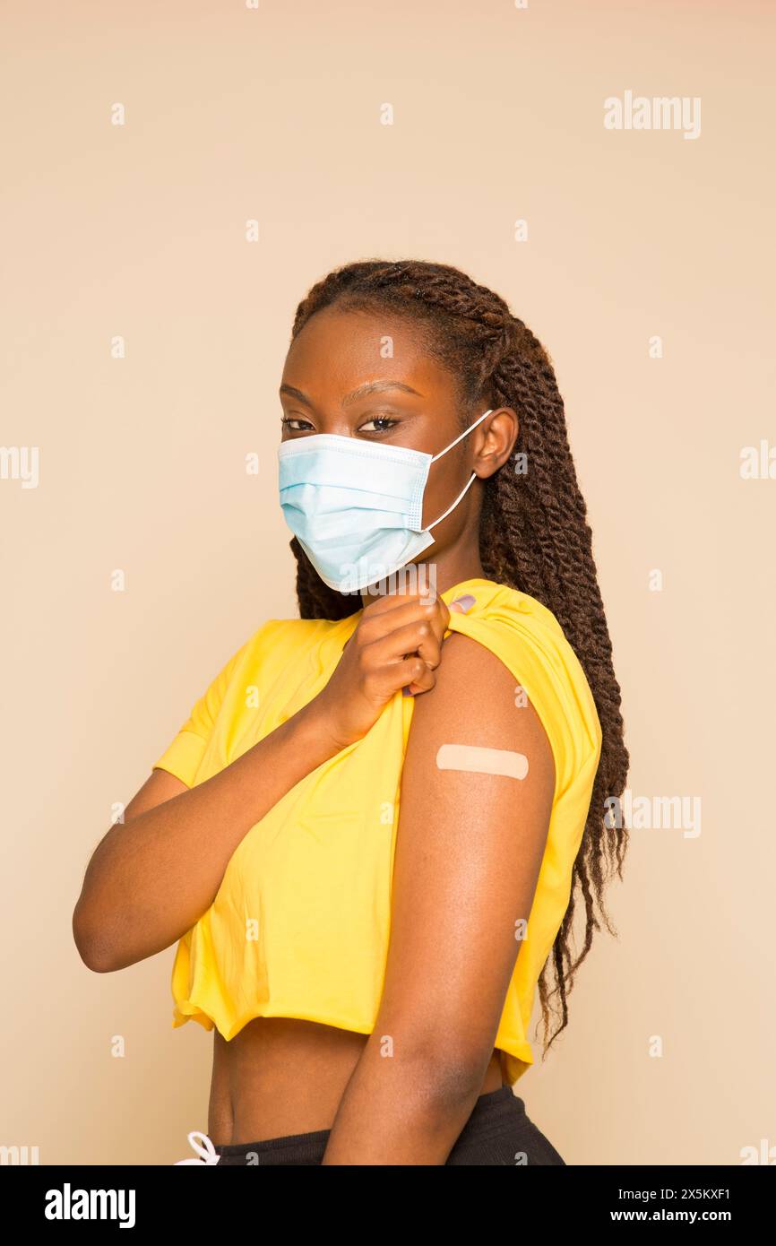 Studio portrait of woman with face mask and adhesive bandage after ...