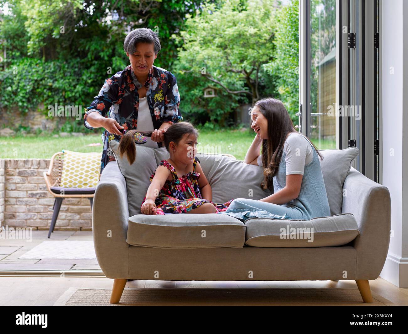Grandmother brushing granddaughters hair on sofa Stock Photo - Alamy